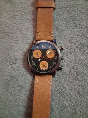 chronograph watch with a black face, orange subdials, and a brown ...