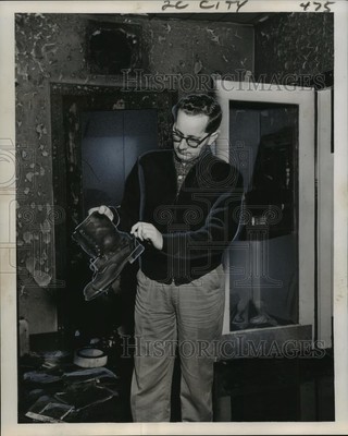 1961 Press Photo Cecil Buchanan holding Glen F. Dastugue's boot whom he ...