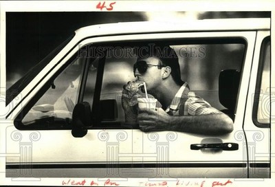 1985 Press Photo David Sprague takes advantage of a stop sign to eat ...