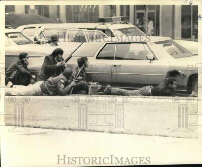 1973 Press Photo Police officers take cover beside a car, armed with ...