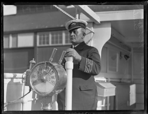 Captain Fisher of the S.S. Calula standing next to the wheel on th ...
