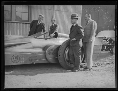 Four men standing beside Wizard Smith in his car the Anzac, NSW, 1- Old ...
