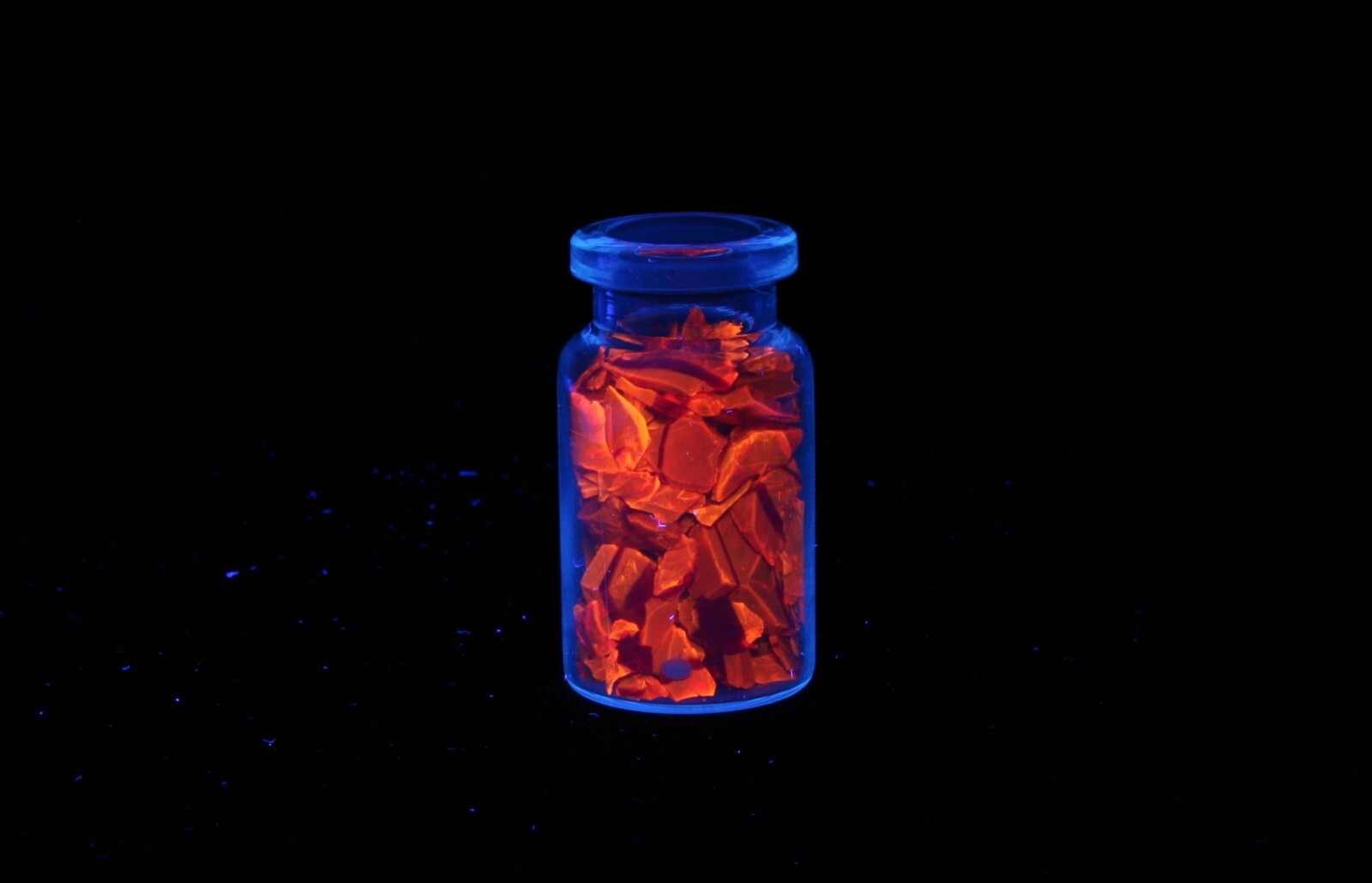 LOOSE SELENIUM GLASS PIECES IN A DISPLAY BOTTLE SHOWING ORANGE UV ...