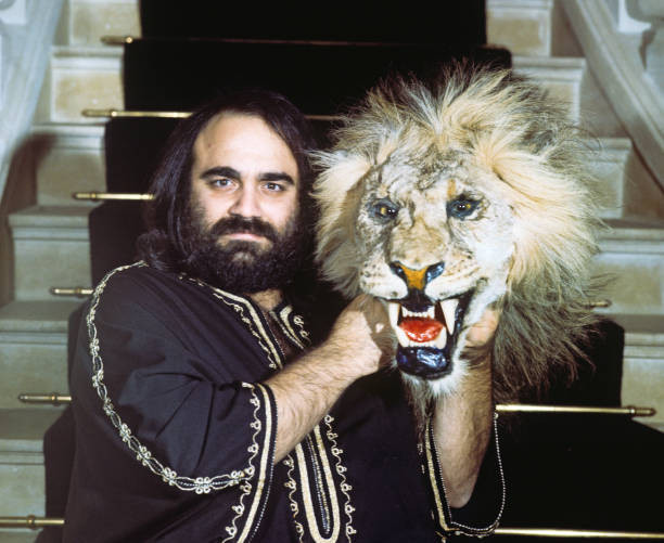 Greek pop singer Demis Roussos posing on a staircase a lion skin ta ...